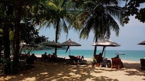 Uma praia com palmeiras, espreguiçadeiras e guarda-sóis.