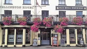 Hotel Wellington e Cervejaria Old Mill, com varandas decoradas com flores cor-de-rosa.