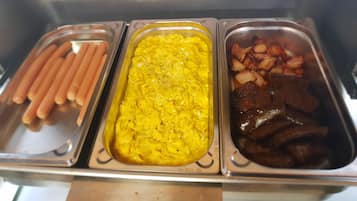 Buffet com cachorros-quentes, ovos mexidos e carnes assadas.