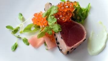 Prato com peixe, caviar e folhas verdes.