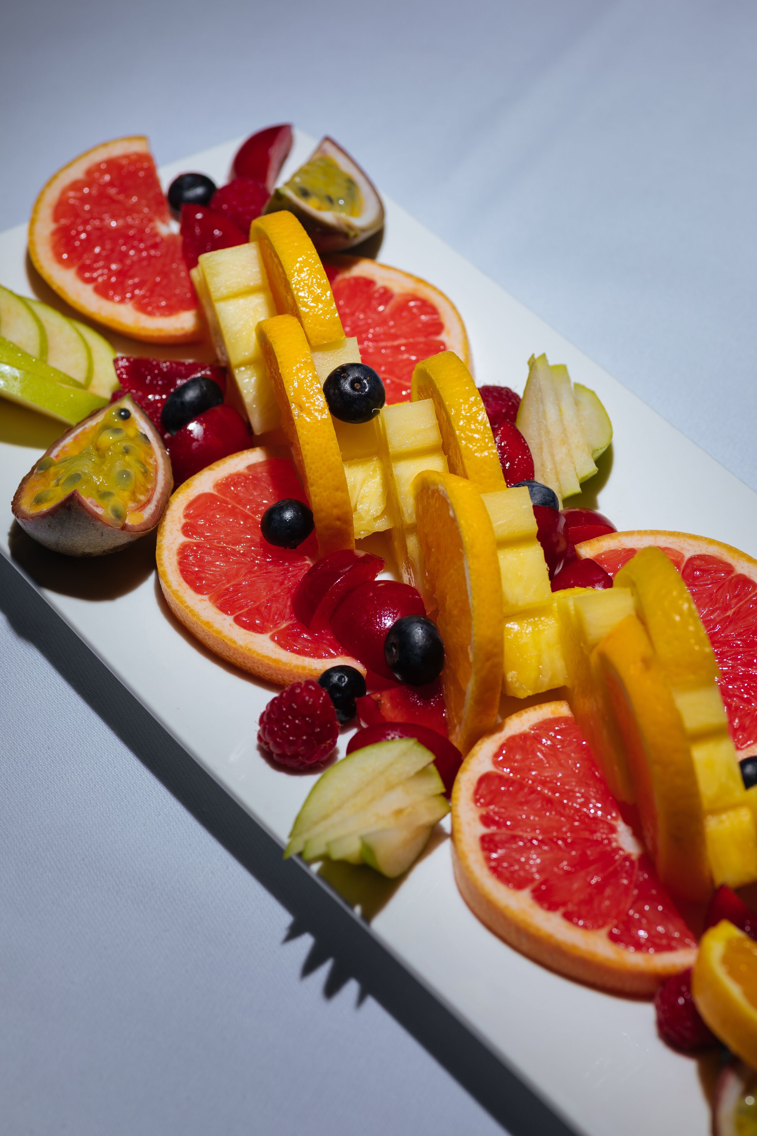 Uma travessa de frutas com diversas opções, incluindo toranja, manga e kiwi.