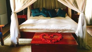 Uma cama com dossel, almofadas e uma decoração em formato de coração na mesa de cabeceira.