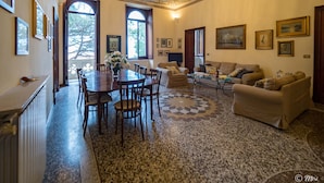 Ampla sala de estar com mesa de jantar redonda, sofás e um candelabro.