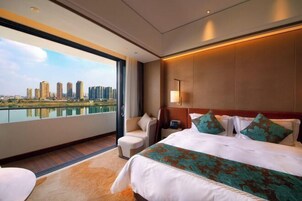 Quarto de hotel moderno com uma cama grande, uma escrivaninha e vista para o horizonte urbano.