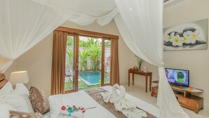 Quarto com cama, TV e vista para uma piscina.