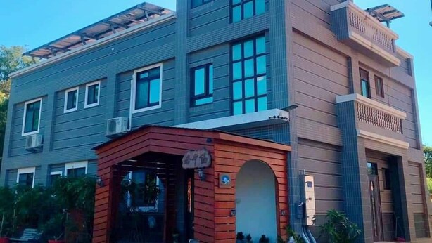 Um edifício de vários andares com telhado plano, janelas amplas e uma pequena entrada com fachada vermelha.