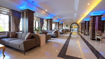 Um hall amplo com sofás, poltronas e um balcão de recepção.