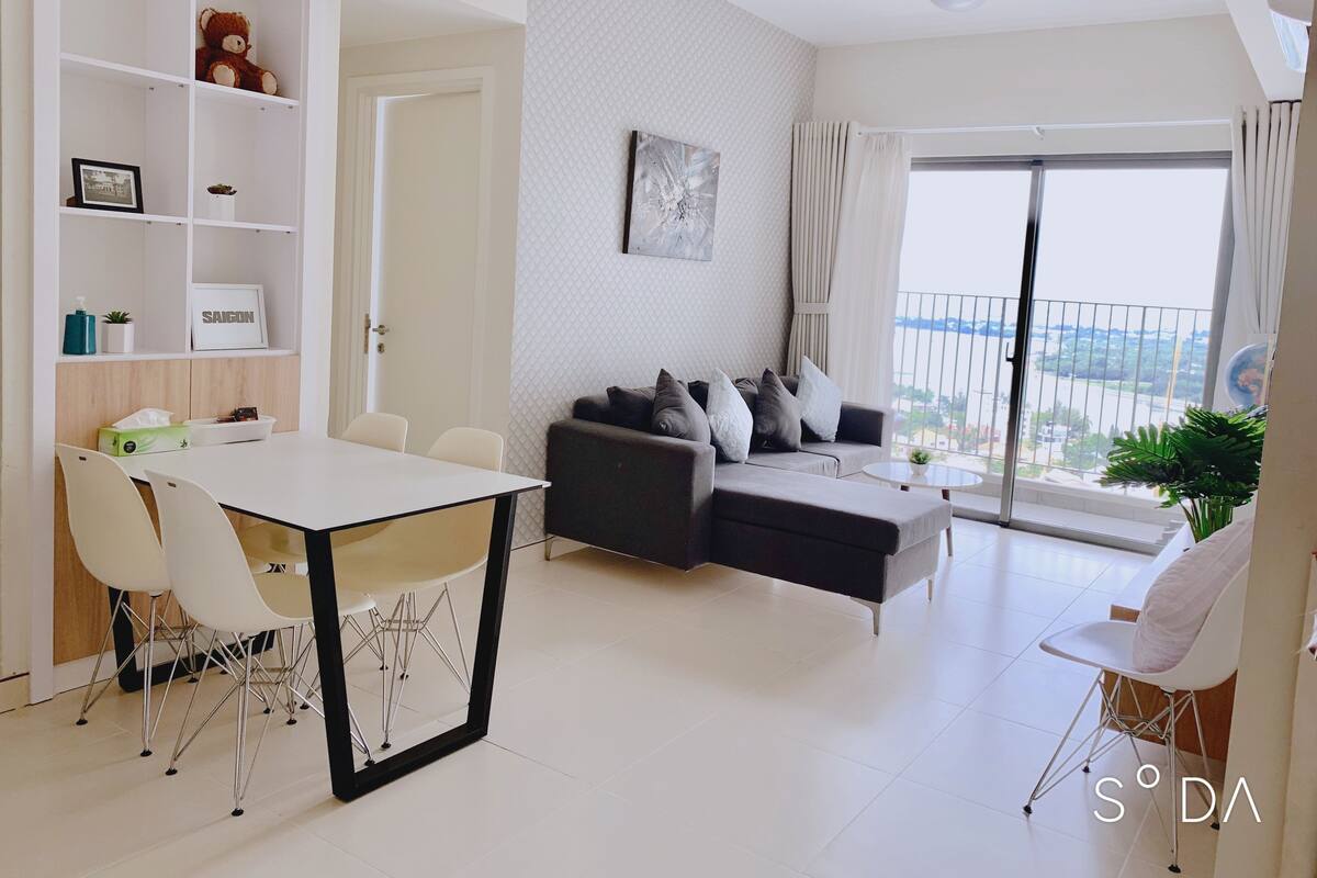 Uma sala de estar moderna com área de jantar, um sofá e uma varanda com vista.