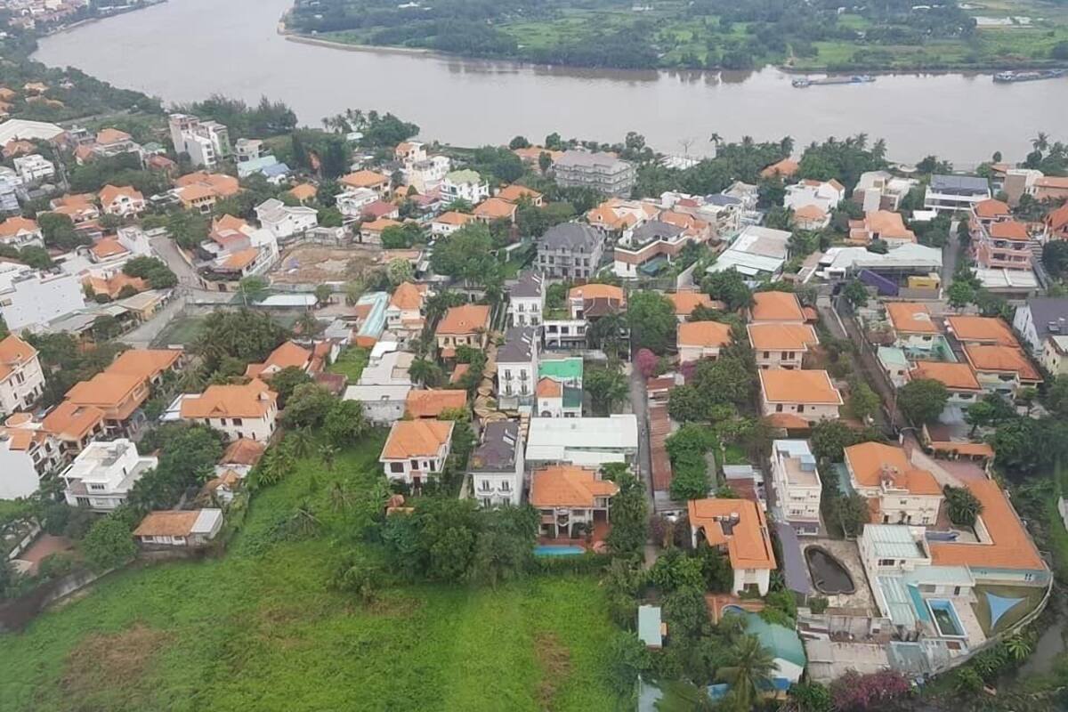 Vista aérea de um bairro residencial com casas, um rio e áreas verdes.