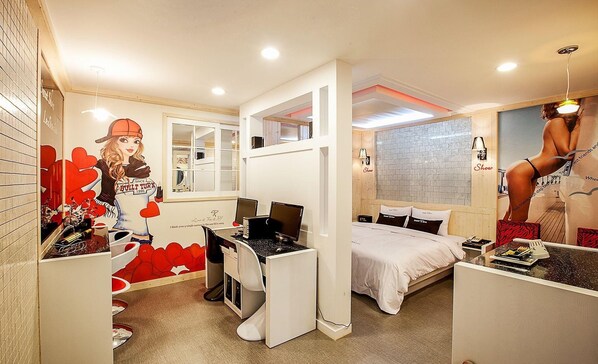 Quarto com cama, escrivaninha e computador. Há uma janela e uma parede com um mural.