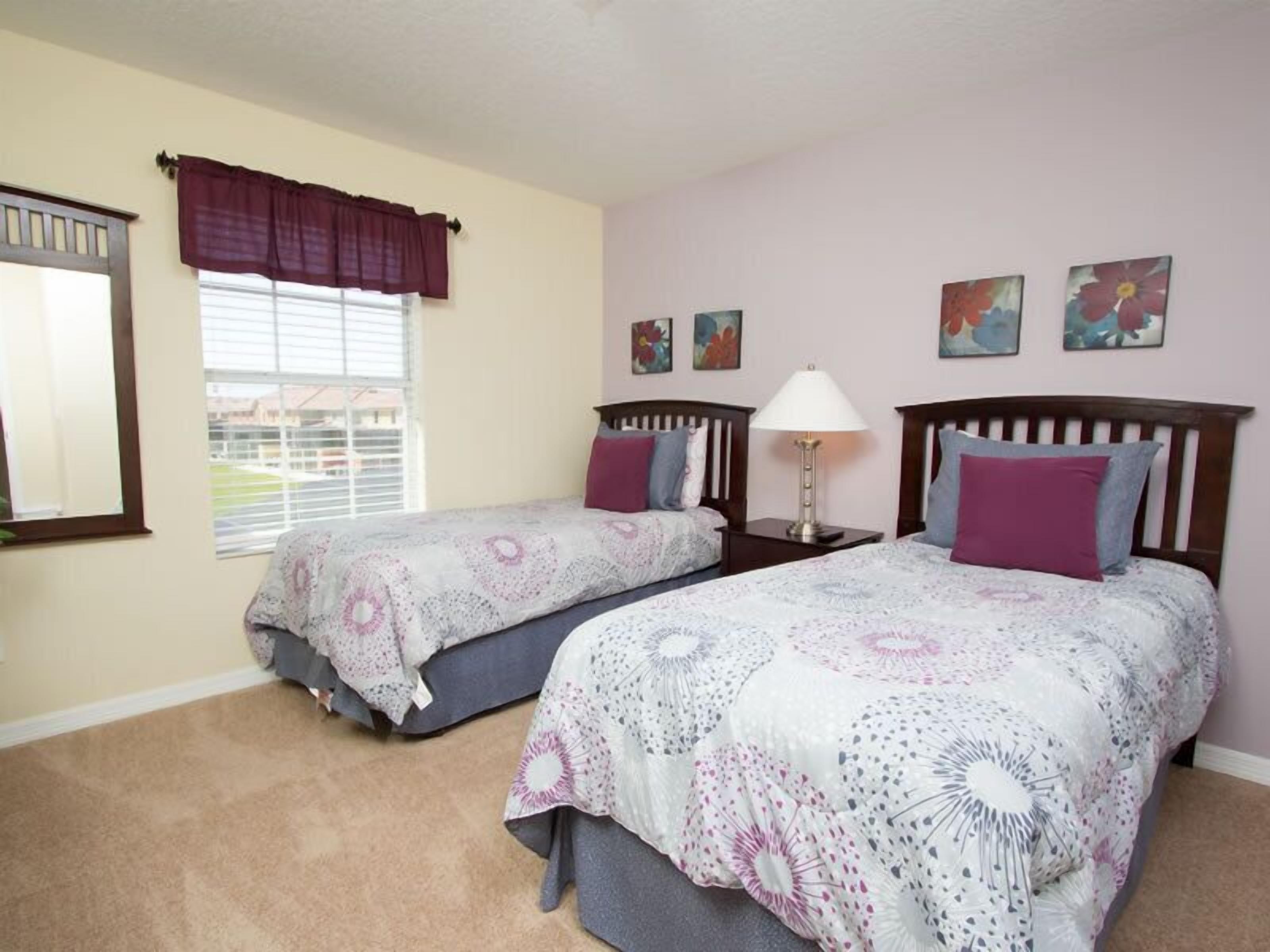 Quarto com duas camas, janela com persianas e mesa de cabeceira com abajur.