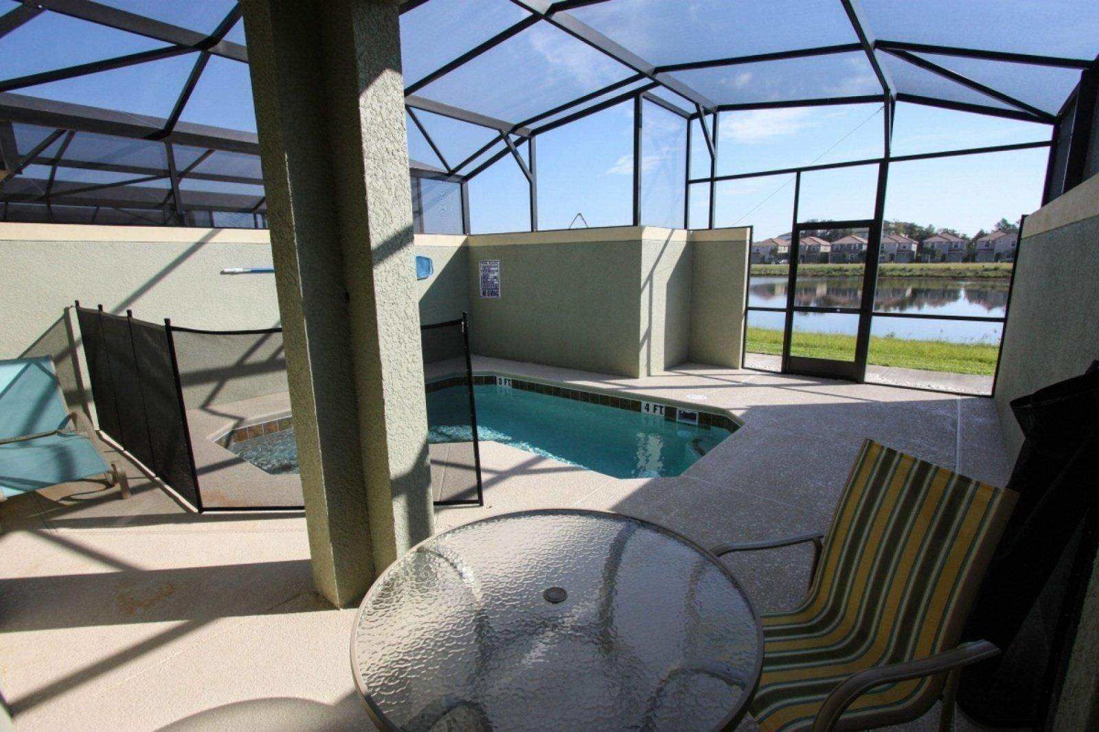 Área de piscina descoberta coberta, com vista para um lago e casas ao fundo.