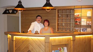 Balcão de recepção com painéis de madeira e duas luminárias pendentes pretas.
