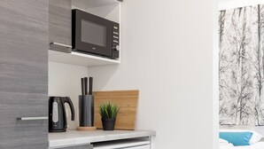 Uma cafeteira/bule, um frigorífico, um micro-ondas 