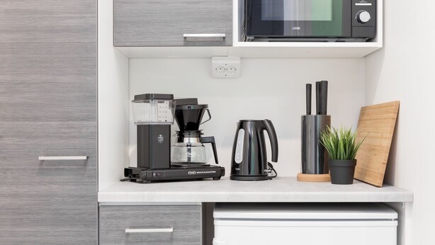 Uma cafeteira/bule, um frigorífico, um micro-ondas 