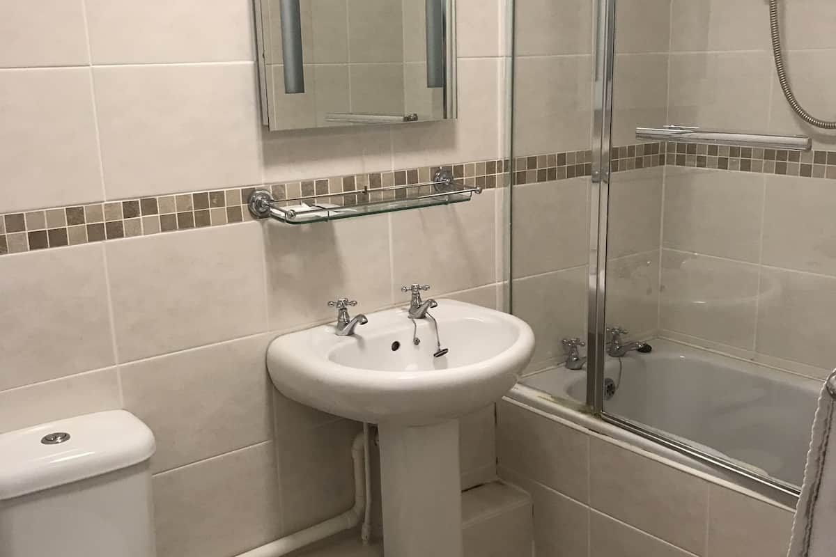 Casa de banho com sanita, lavatório e cabine de duche com vidro.