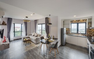 Um apartamento moderno com sala de estar, área de jantar e cozinha. Possui janelas grandes, varanda e vista para a cidade.