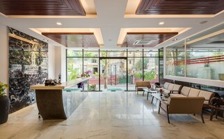 Um saguão moderno com uma receção em mármore, assentos confortáveis, grandes janelas e vista para o exterior.
