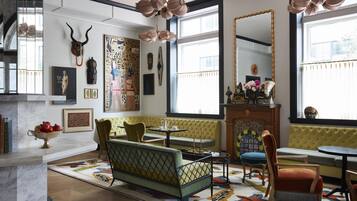 Um quarto com sofá, cadeiras, uma mesa, lareira e diversas decorações nas paredes.