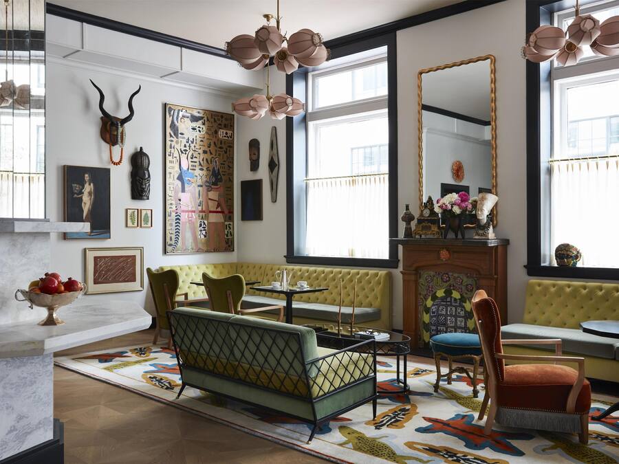 Um quarto com sofá, cadeiras, uma mesa, lareira e diversas decorações nas paredes.