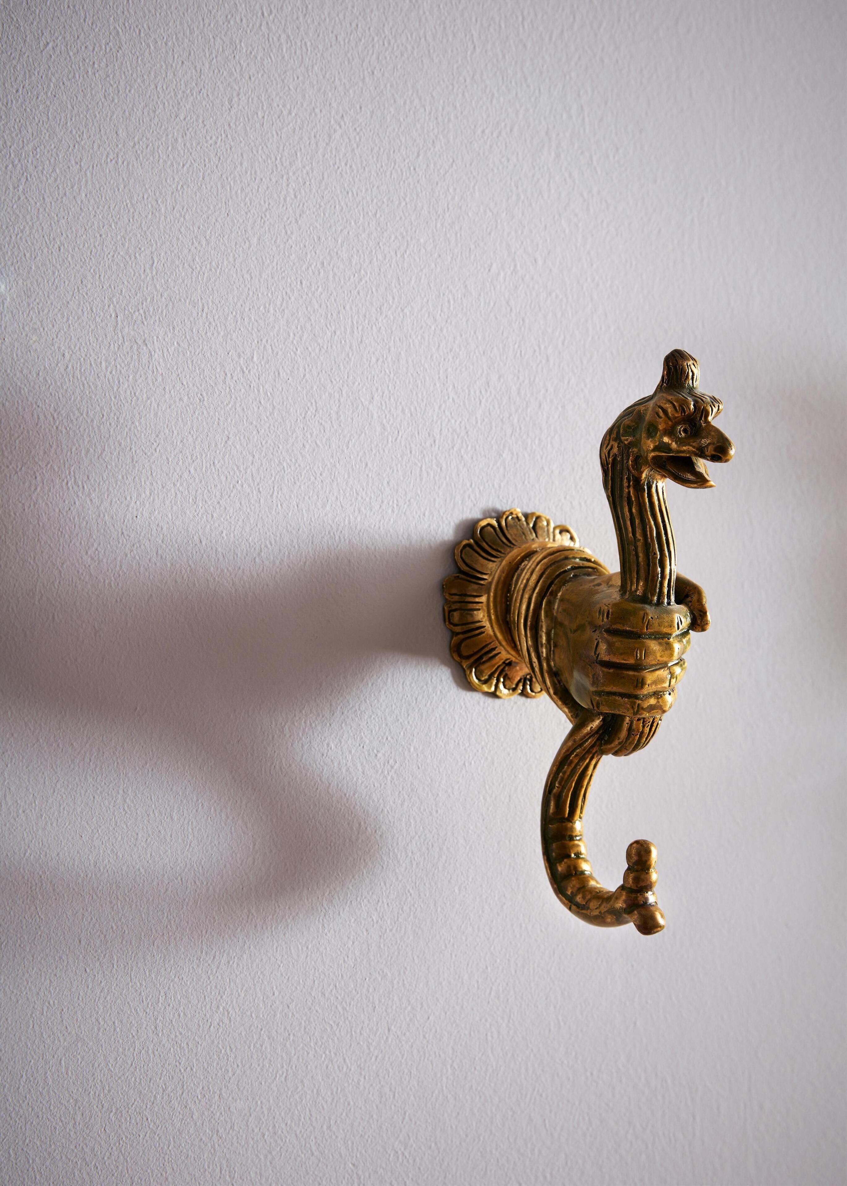 Puxador metálico ornamentado, fixado na parede, com motivo de cavalo.