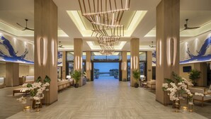 Um hall amplo com um lustre moderno, áreas de estar e vista para o exterior.