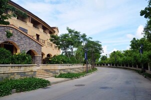 Um edifício com fachada de pedra, várias varandas e uma entrada com caminho curvo.