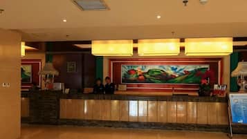 Uma área de recepção de hotel com balcão de mármore, uma pintura grande na parede e um balcão de atendimento.