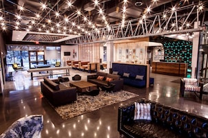 Um hall amplo com mesa de bilhar, sofás e área de bar com obras de arte.