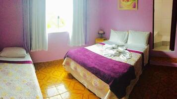 Quarto com cama, mesa de cabeceira e janela com cortinas.