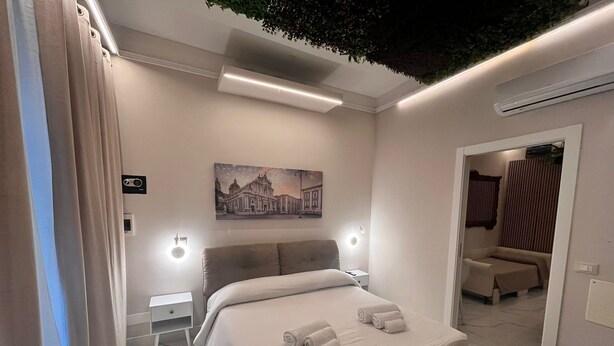 Quarto de hotel moderno com uma cama grande, um quadro na parede e um espelho refletindo o ambiente.