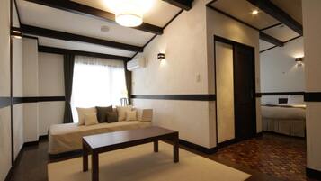 Quarto de hotel com cama, sofá, mesa e piso de madeira.