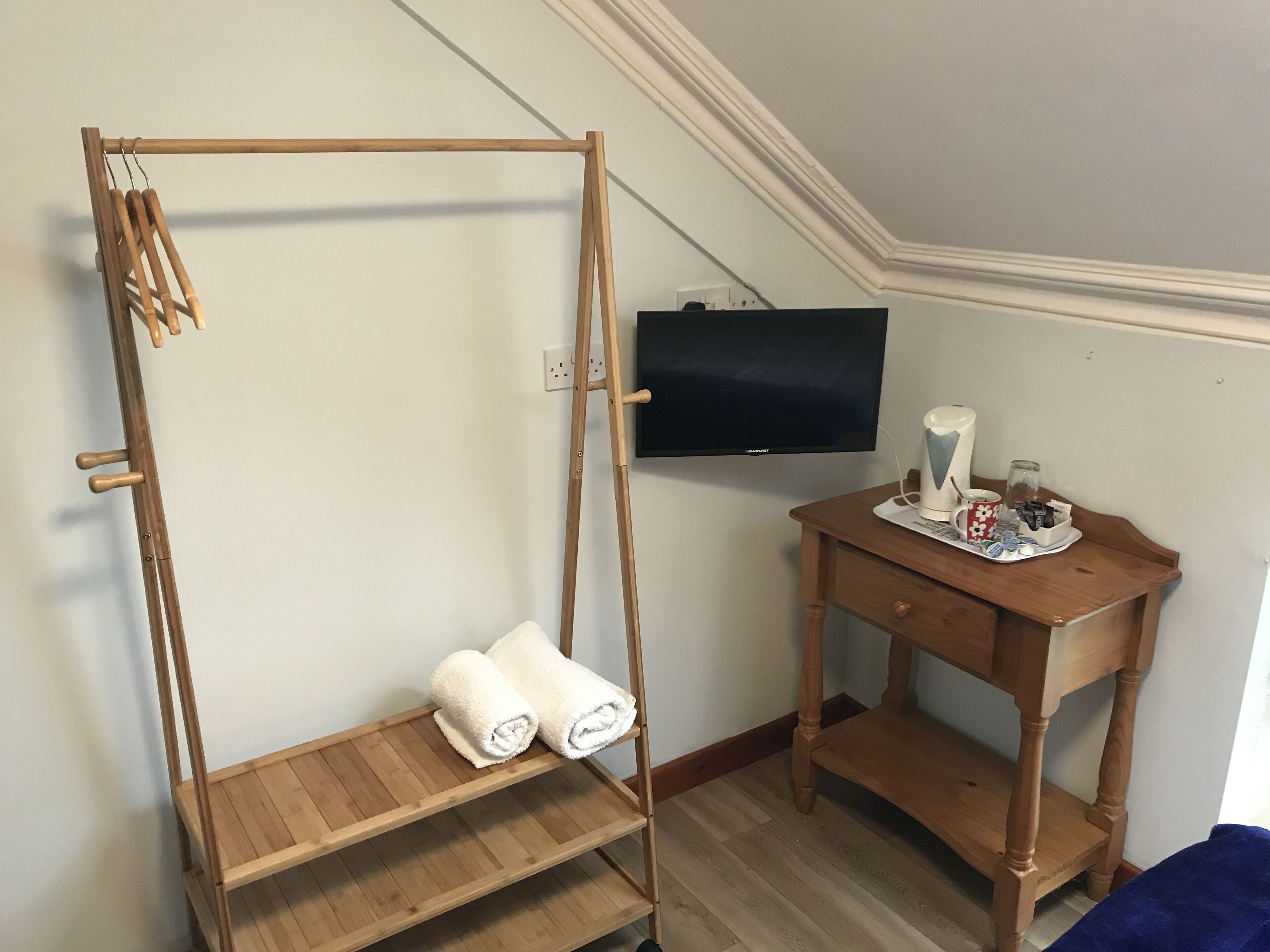 Quarto com cadeira de balanço de madeira, televisão de tela plana e uma pequena mesa de madeira com bandeja.