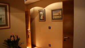 Um corredor com piso de madeira, uma porta e duas quadros na parede.