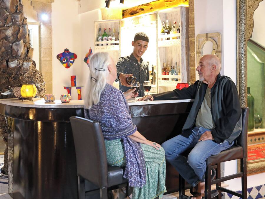 Uma área de bar com parede de pedra, balcão e espelho.