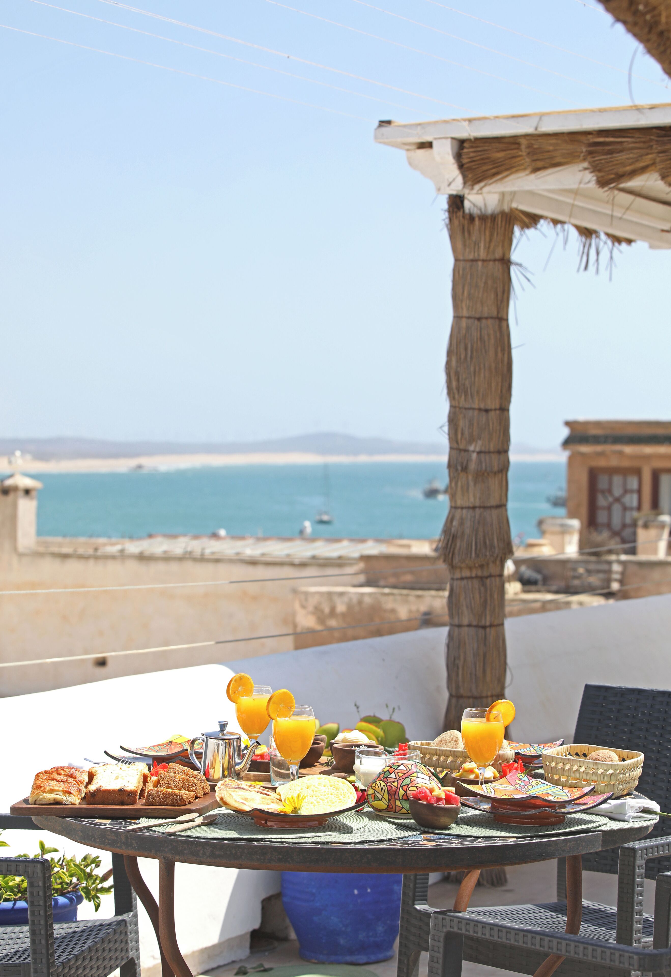 Mesa posta com itens de café da manhã e vista para o mar.
