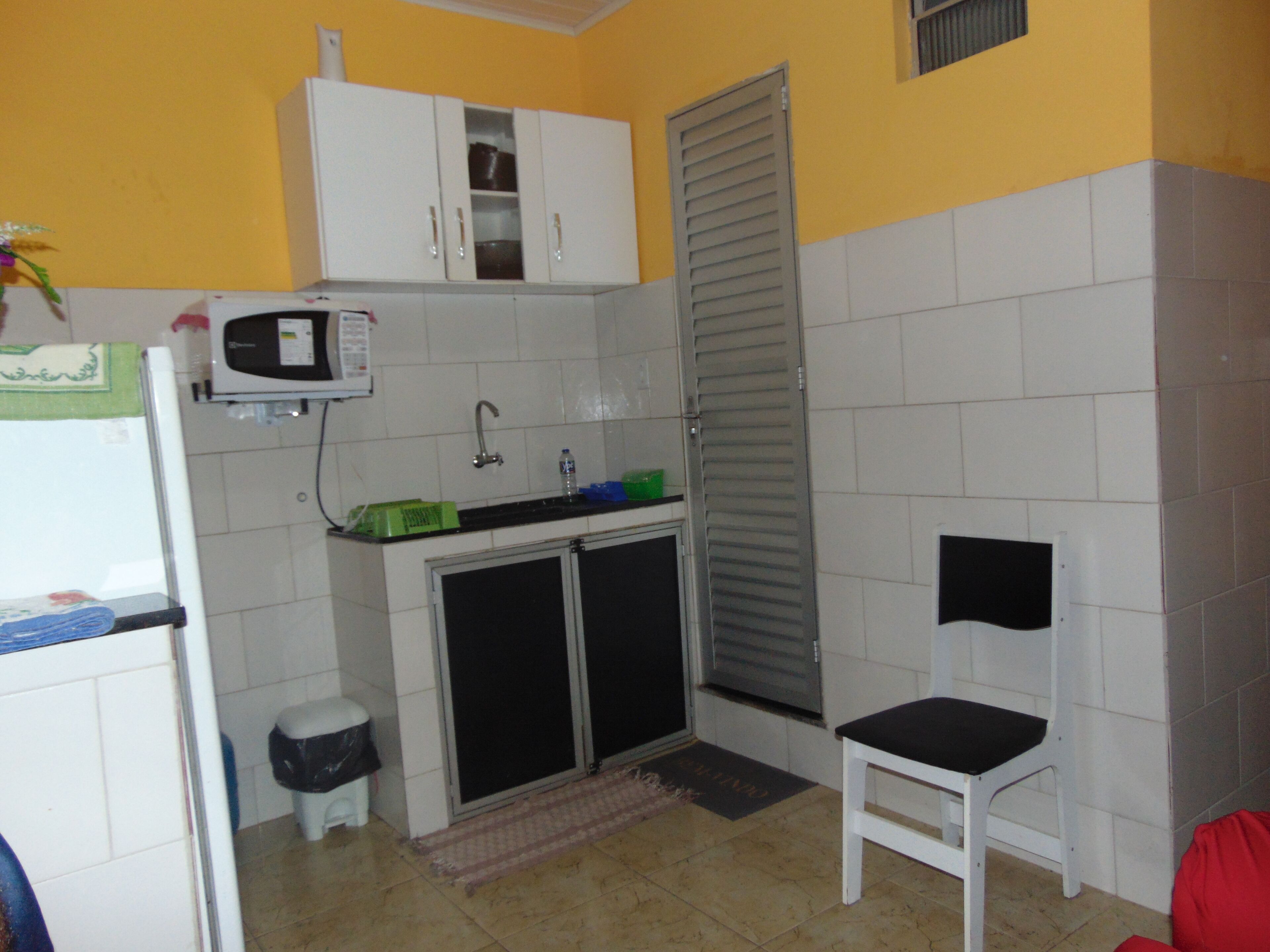 Cozinha compacta com micro-ondas, pia e armários.