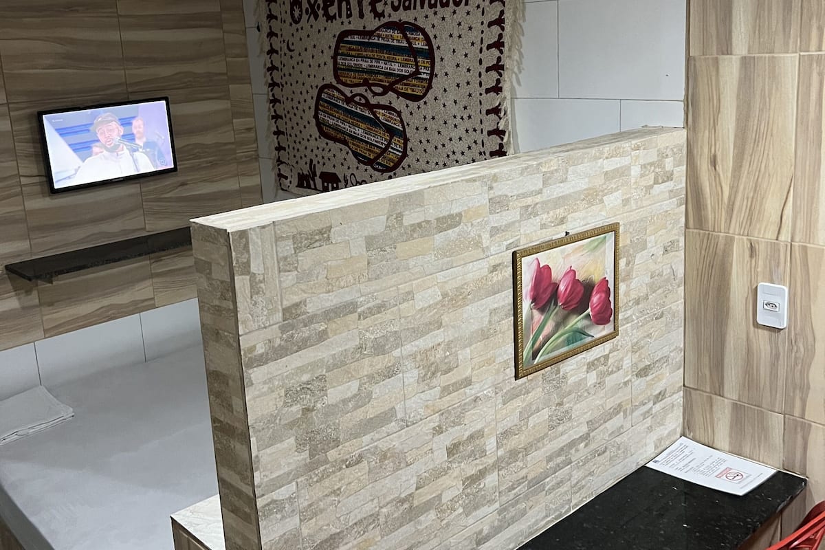 Uma casa de banho moderna com zona de duche, toucador com espelho e televisão na parede.