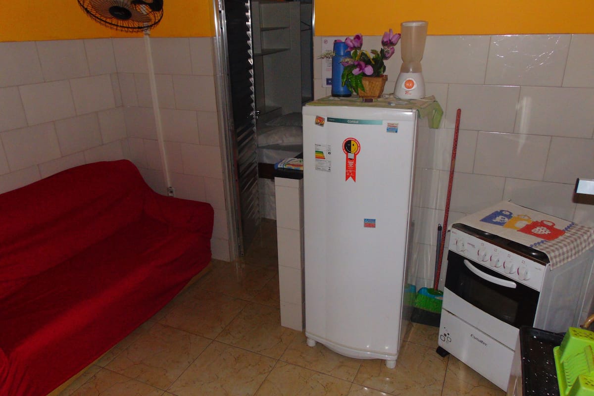 Cozinha compacta com geladeira, fogão e micro-ondas.