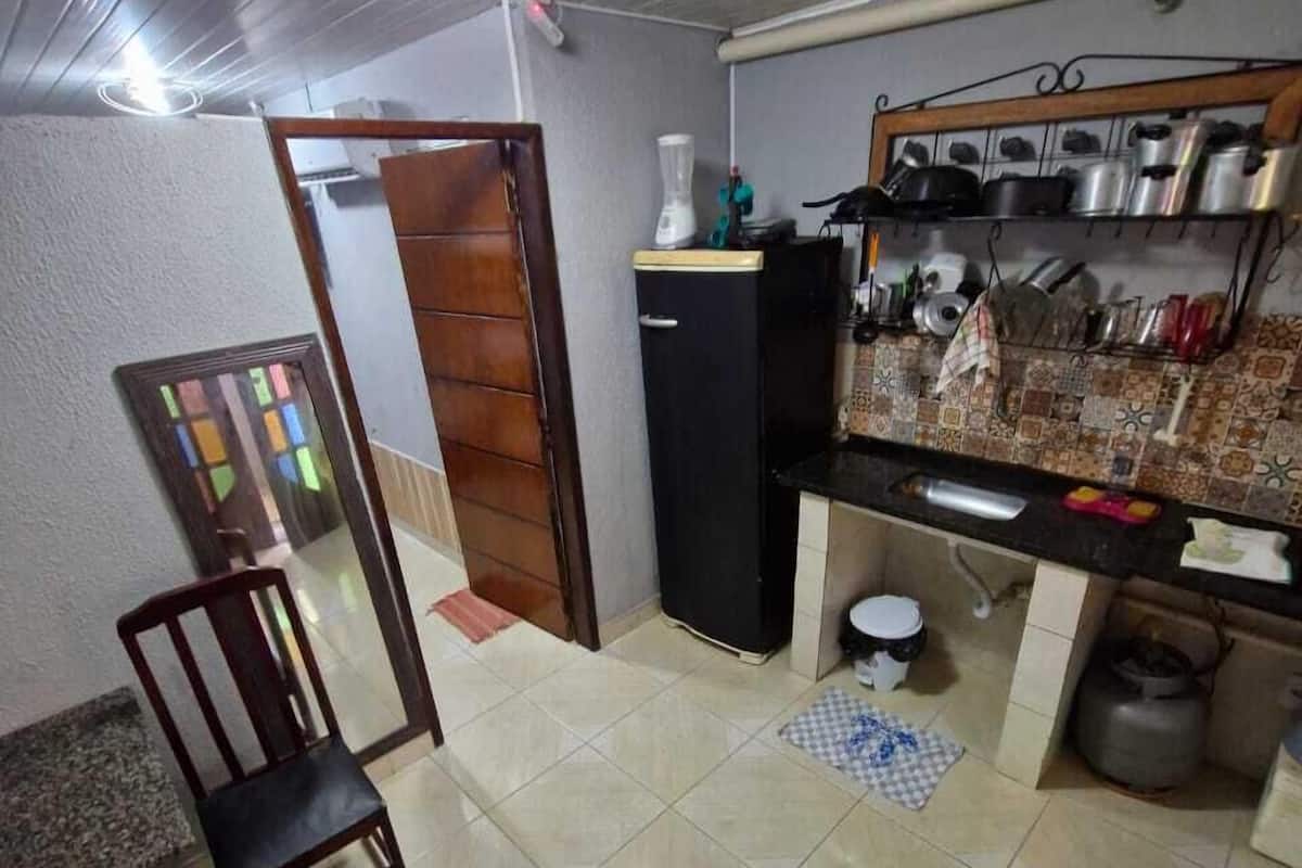 Uma cozinha compacta com geladeira, pia e piso ladrilhado.