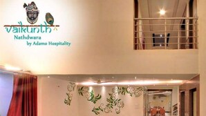 Um hall de hotel com um conjunto de sofás, uma mesa de centro, arte decorativa na parede e uma escada ao fundo.