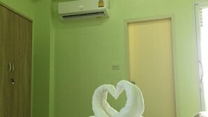 Quarto de hotel com cama, guarda-roupa de madeira, porta e ar condicionado.