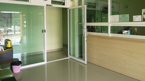 Uma área de recepção moderna com portas de vidro, um relógio e um balcão de atendimento.
