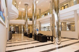 Um hall amplo com teto alto, piso de mármore polido e móveis modernos.
