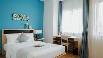 Quarto de hotel moderno com cama, escrivaninha e janela com cortinas.