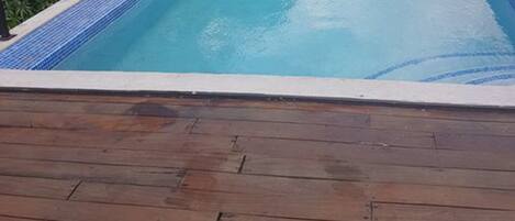 Piscina retangular com um deque de madeira em primeiro plano.