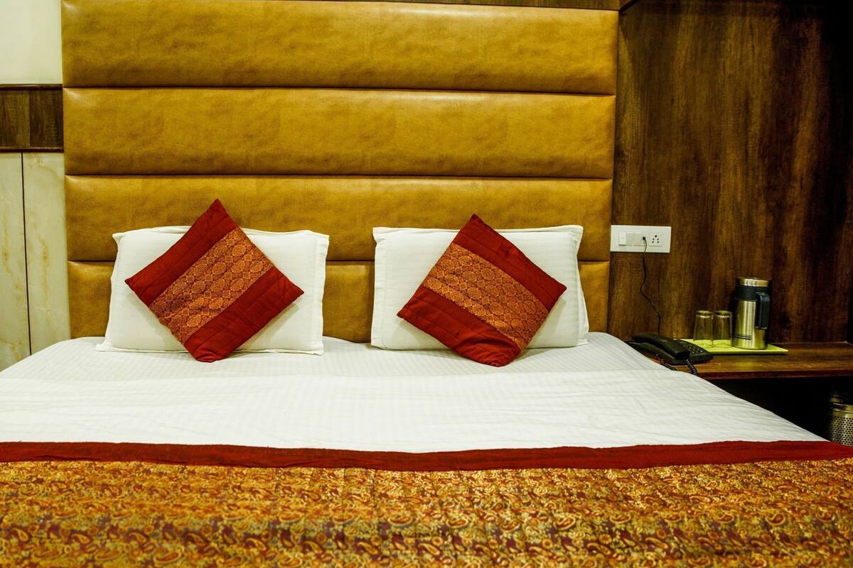 Quarto de hotel com uma cama grande, duas almofadas, mesa de cabeceira com telefone e apoio de mesa com cafeteira.
