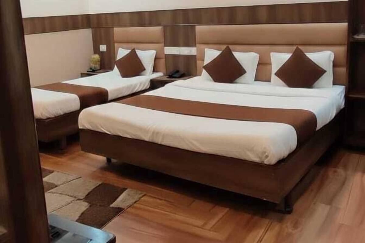 Quarto de hotel com duas camas, piso de madeira e ventoinha no teto.