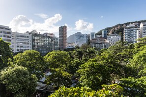 Paisagem urbana com edifícios modernos, vegetação densa e céu claro.