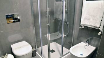 Uma casa de banho moderna com chuveiro envolto em vidro, sanita e lavatório.